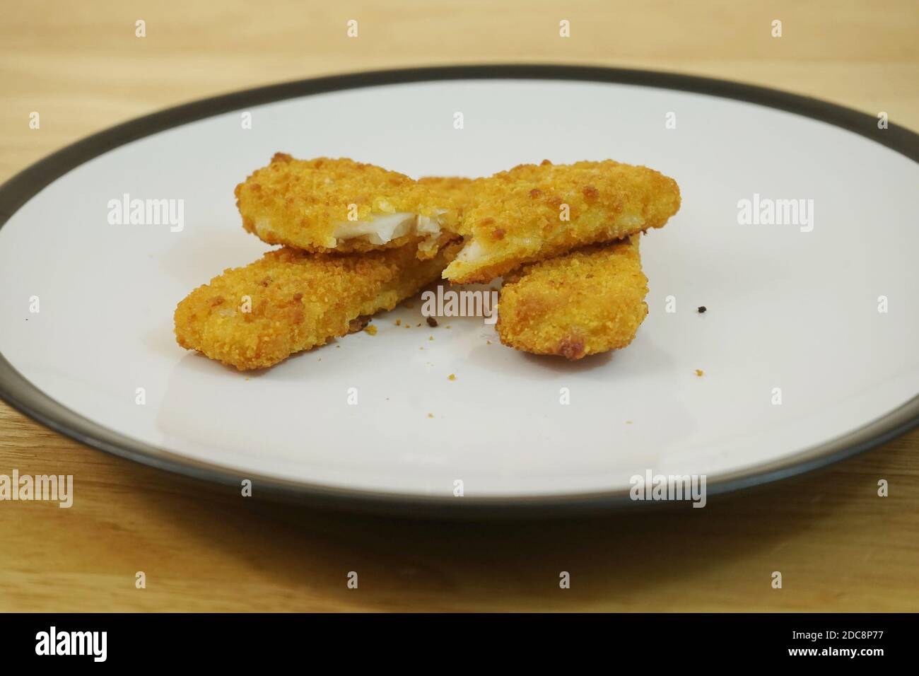 Three Cod fish fingers on a plain plate Stock Photo - Alamy