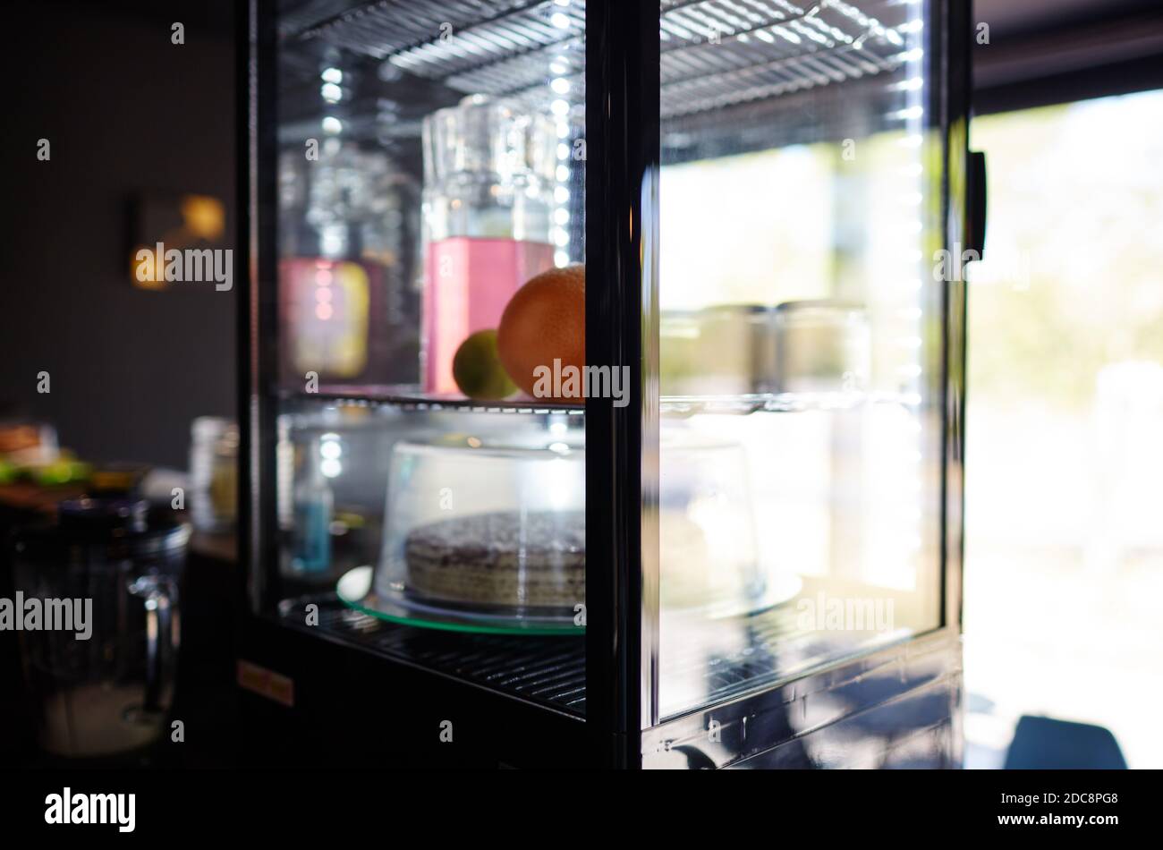 Blurry image of Showcase in cafe shop. Cake and jug with drink on the ...