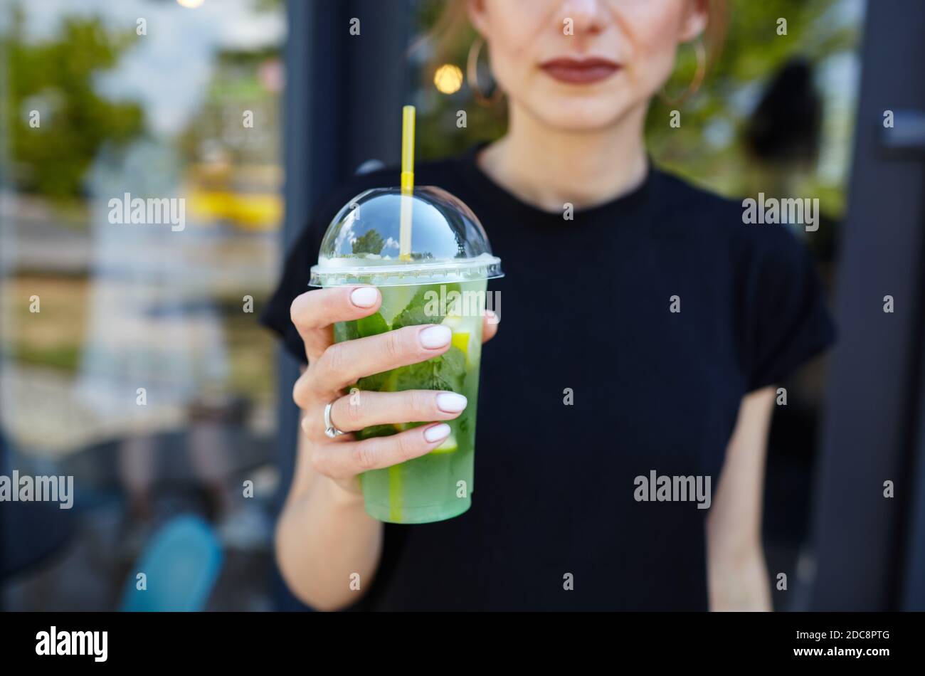 Female hand holding plastic cup with a mojito in a city cafe. Fresh ...