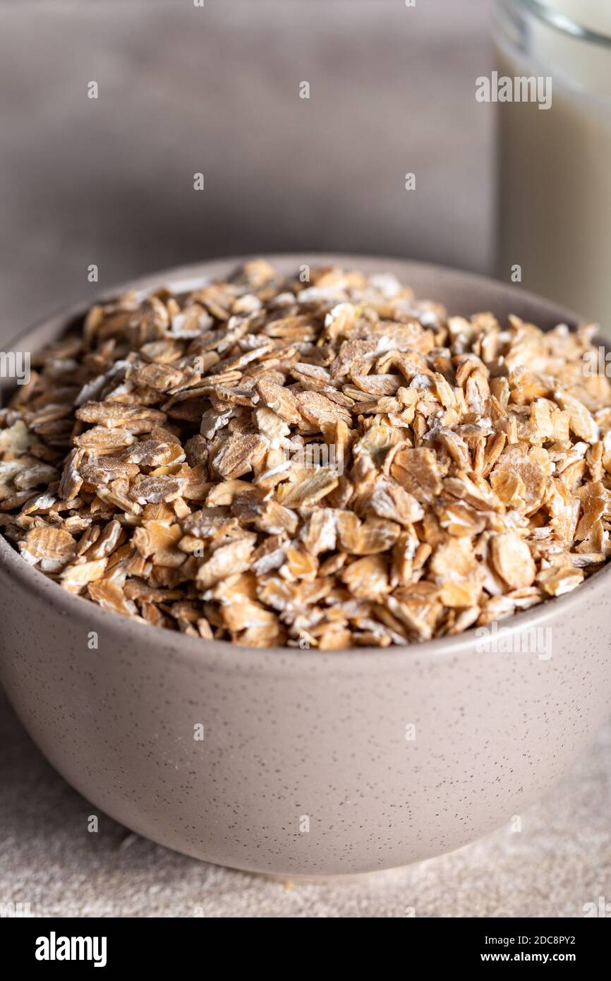 Rye flakes in a bowl with glass of milk on a stone background. Healthy ...