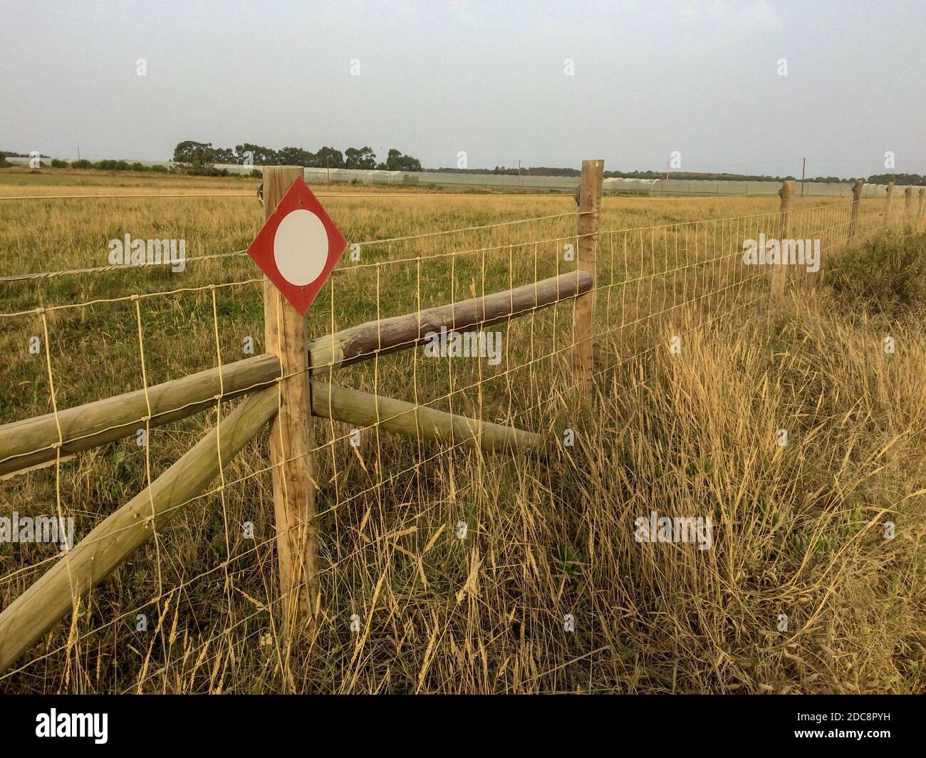 sign on the column with barbed wire, grid with barbed wire, cloudy sky ...