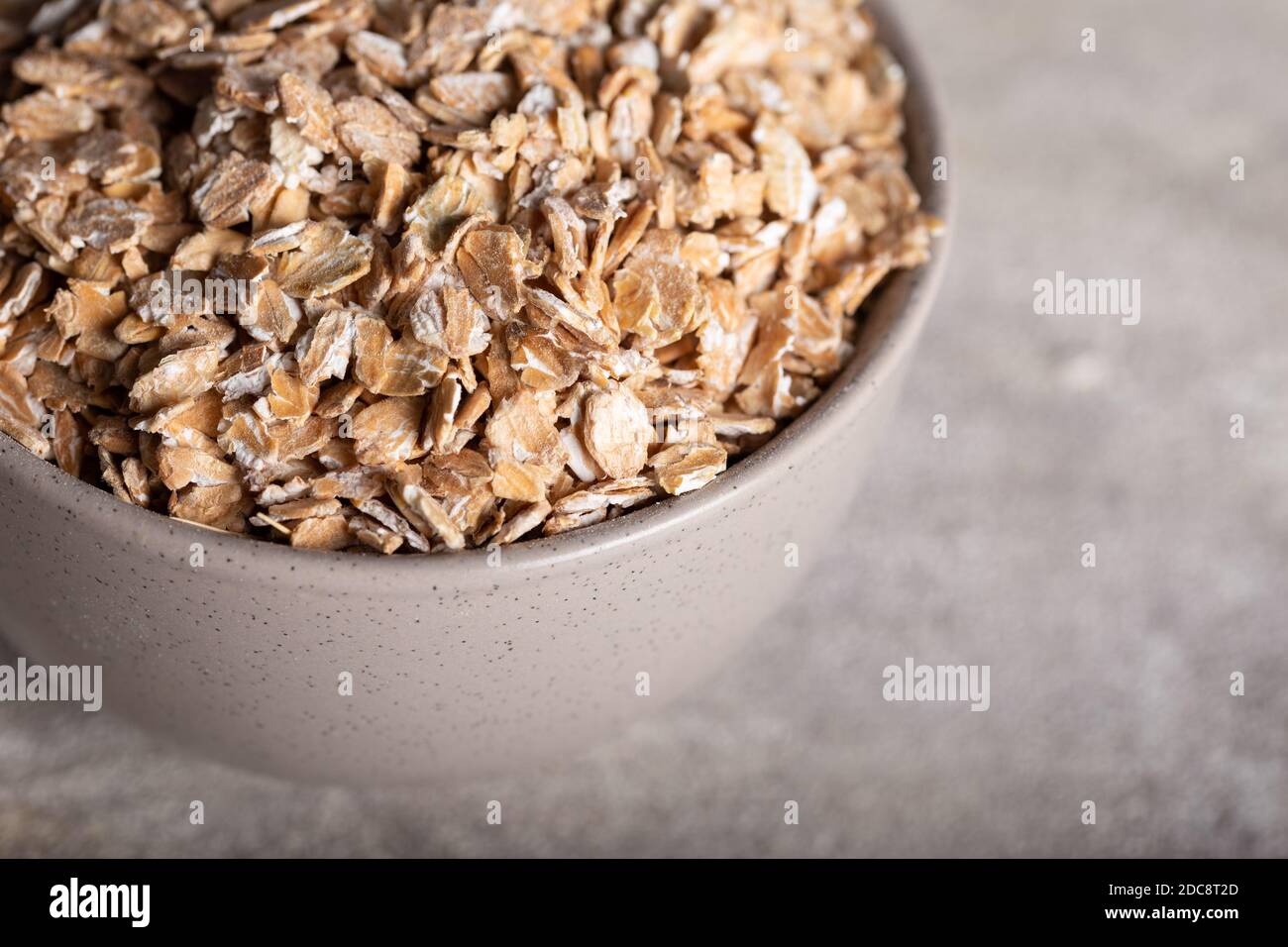 Rye flakes in a bowl with glass of milk on a stone background. Healthy ...