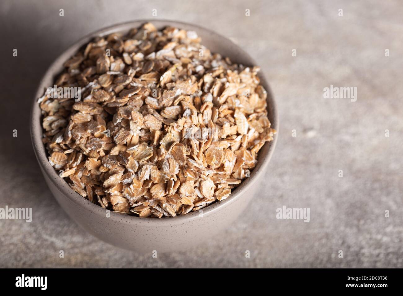 Rye flakes in a bowl with glass of milk on a stone background. Healthy ...