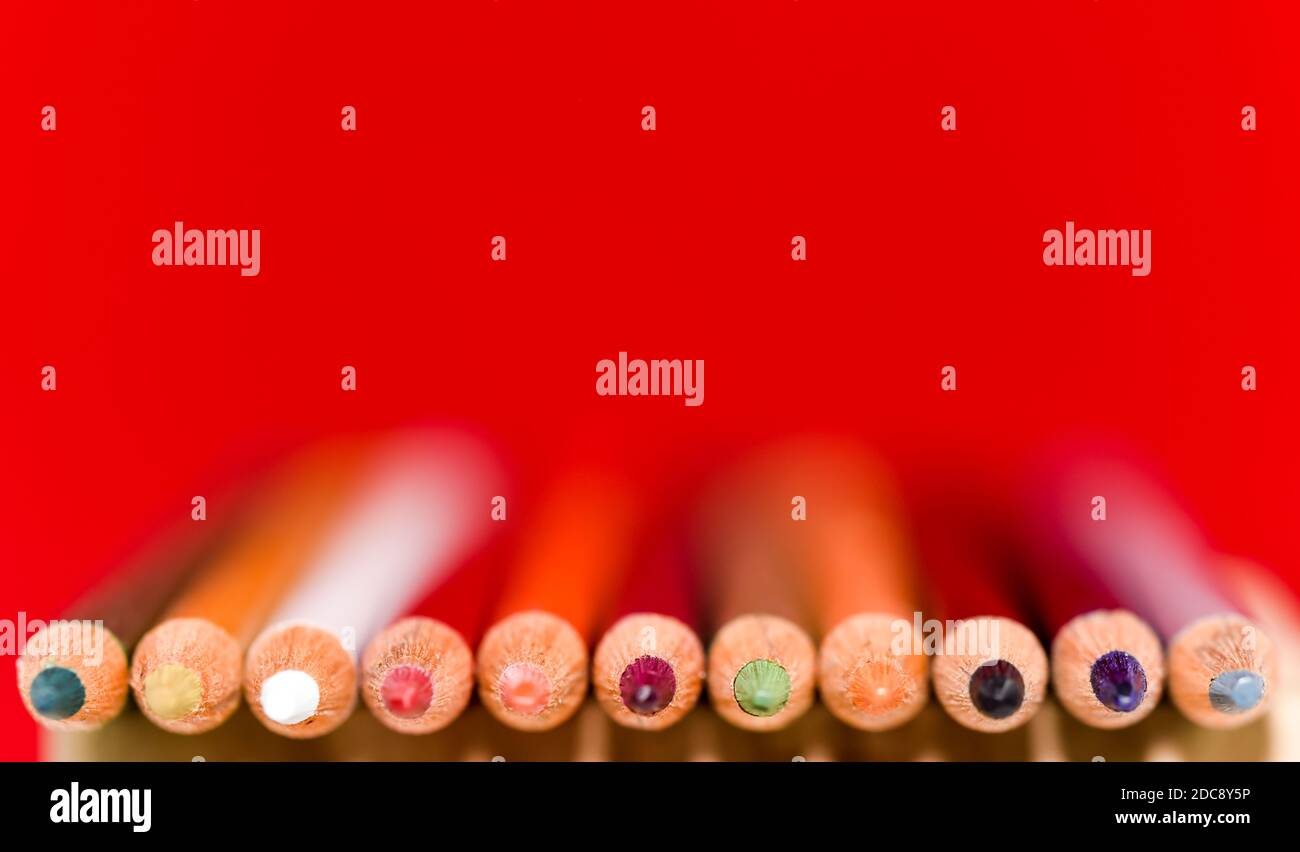 Multi-colored drawing pencils in a row with red background Stock Photo ...
