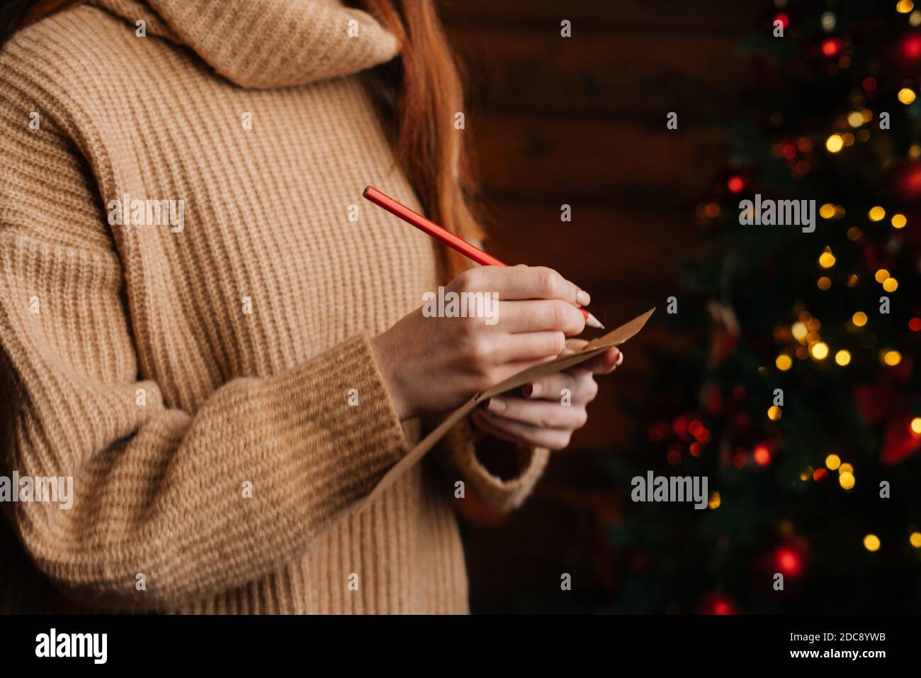 Close-up hands of young woman writing Christmas letter to Santa Claus ...