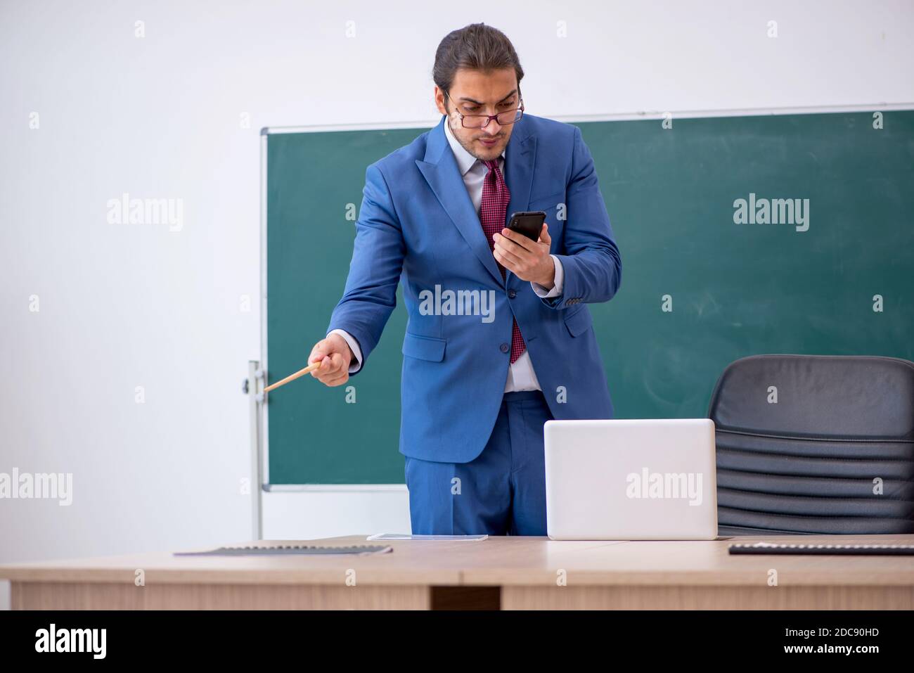 Young teacher in suit in front of green board Stock Photo - Alamy