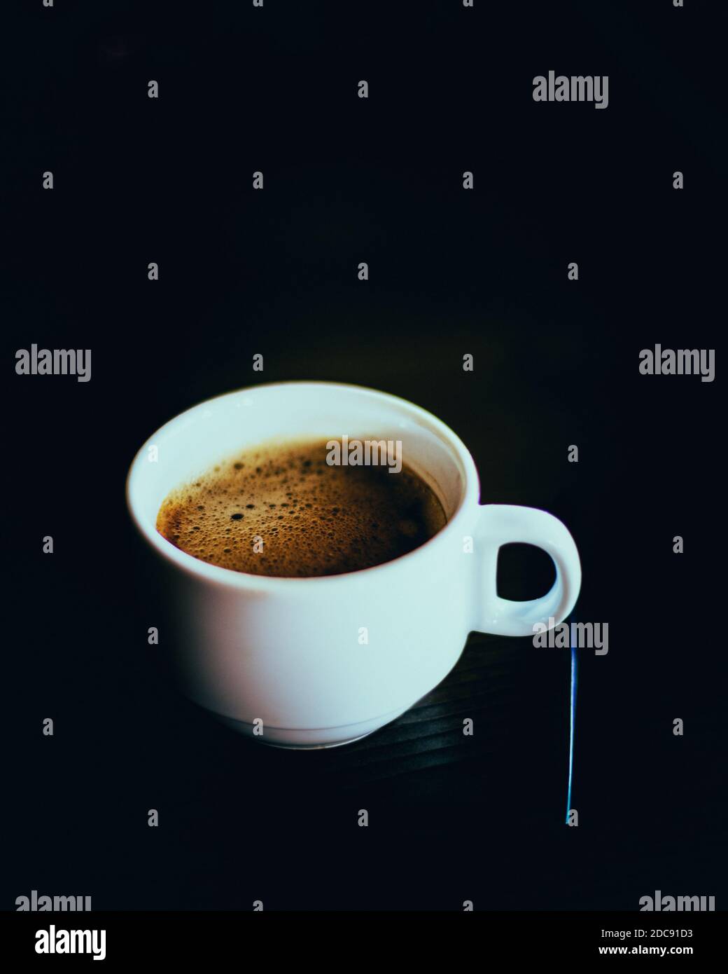 First morning cup of double shot of espresso with stirrer on dark ...