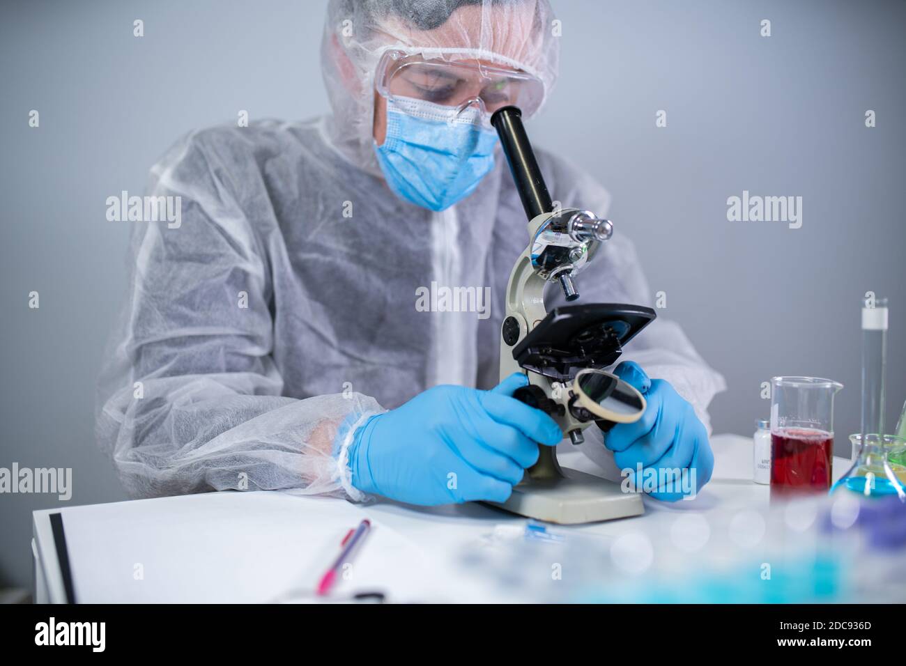 Scientist examining sample with a microscope, doing medical research in ...
