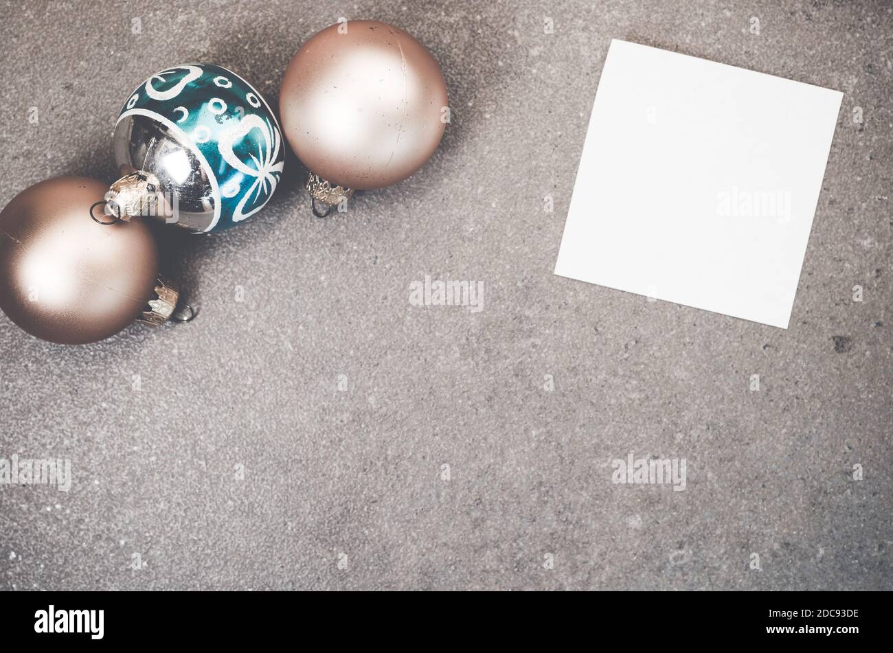 A top view of shiny Christmas ornaments and a black sticky note on a ...