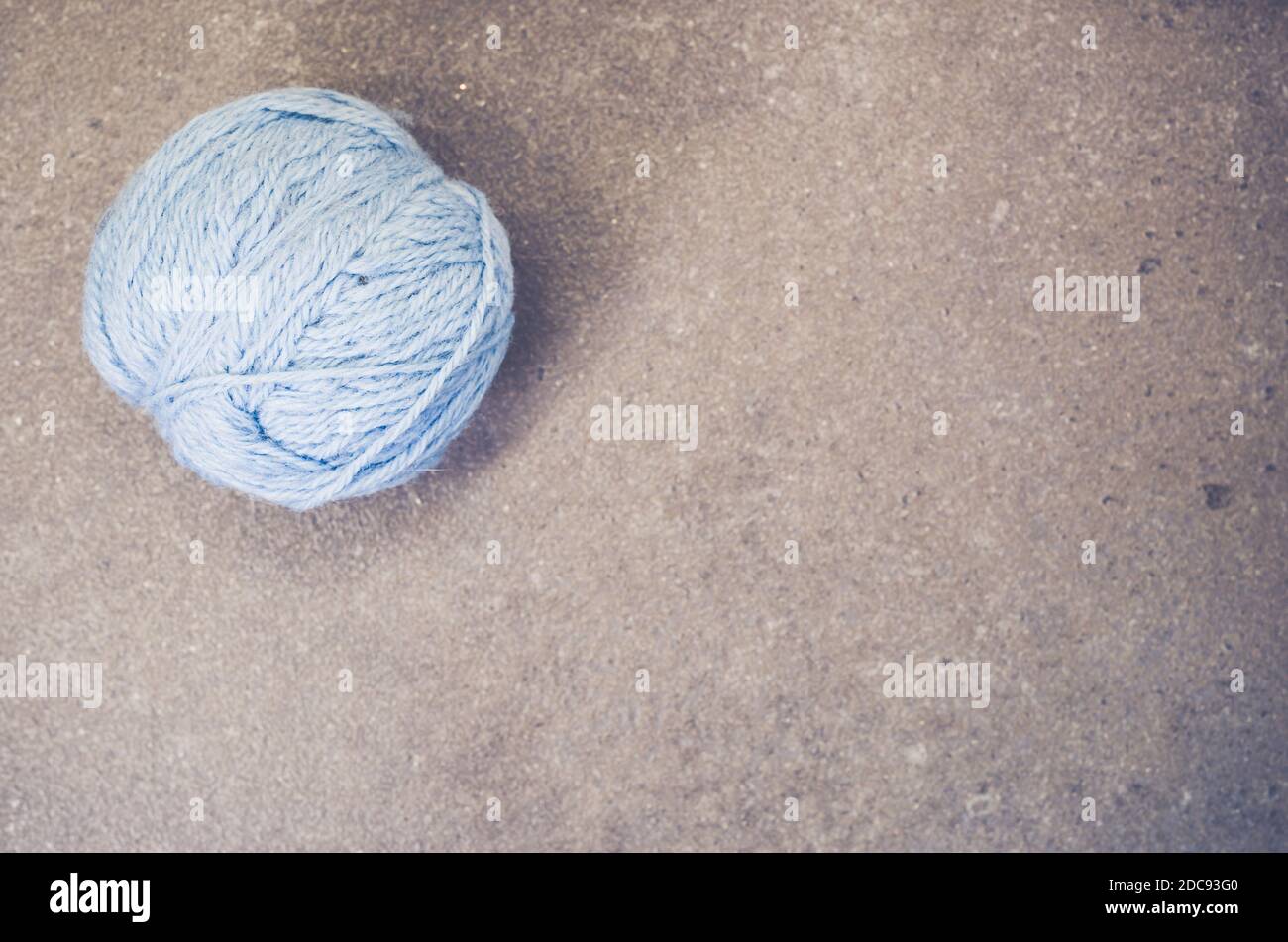 A top view of a ball of light blue yarn on a smooth surface with copy ...