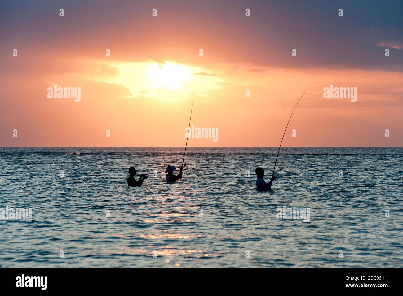 Fisherman fishing at Sunset in teh ocean on Sengiggi Beach, silhouetted ...