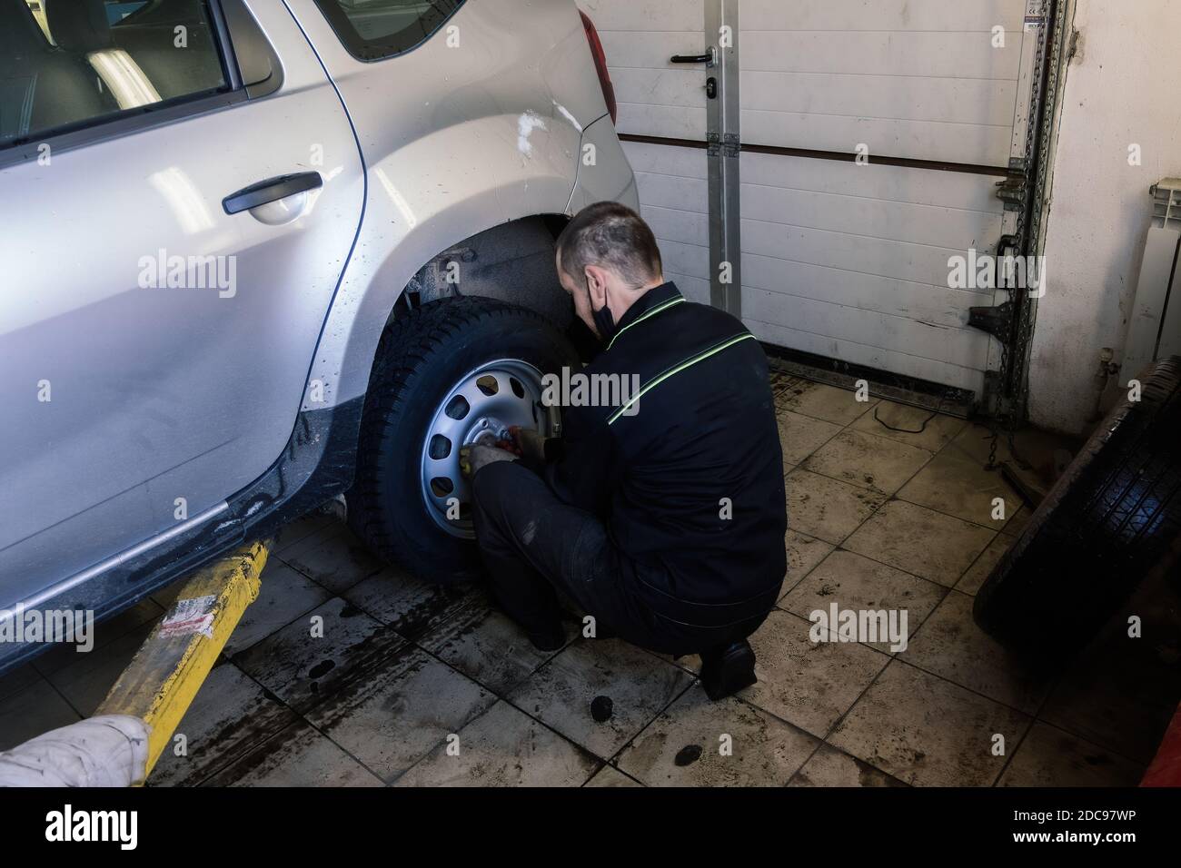 Mechanic changing car wheel in auto service workshop Stock Photo - Alamy