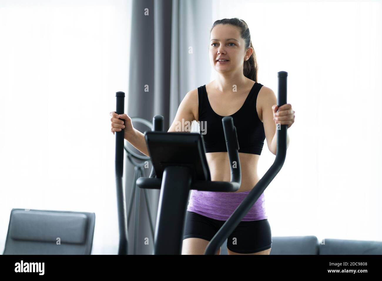 Woman Training On Elliptical Trainer At Home Stock Photo - Alamy