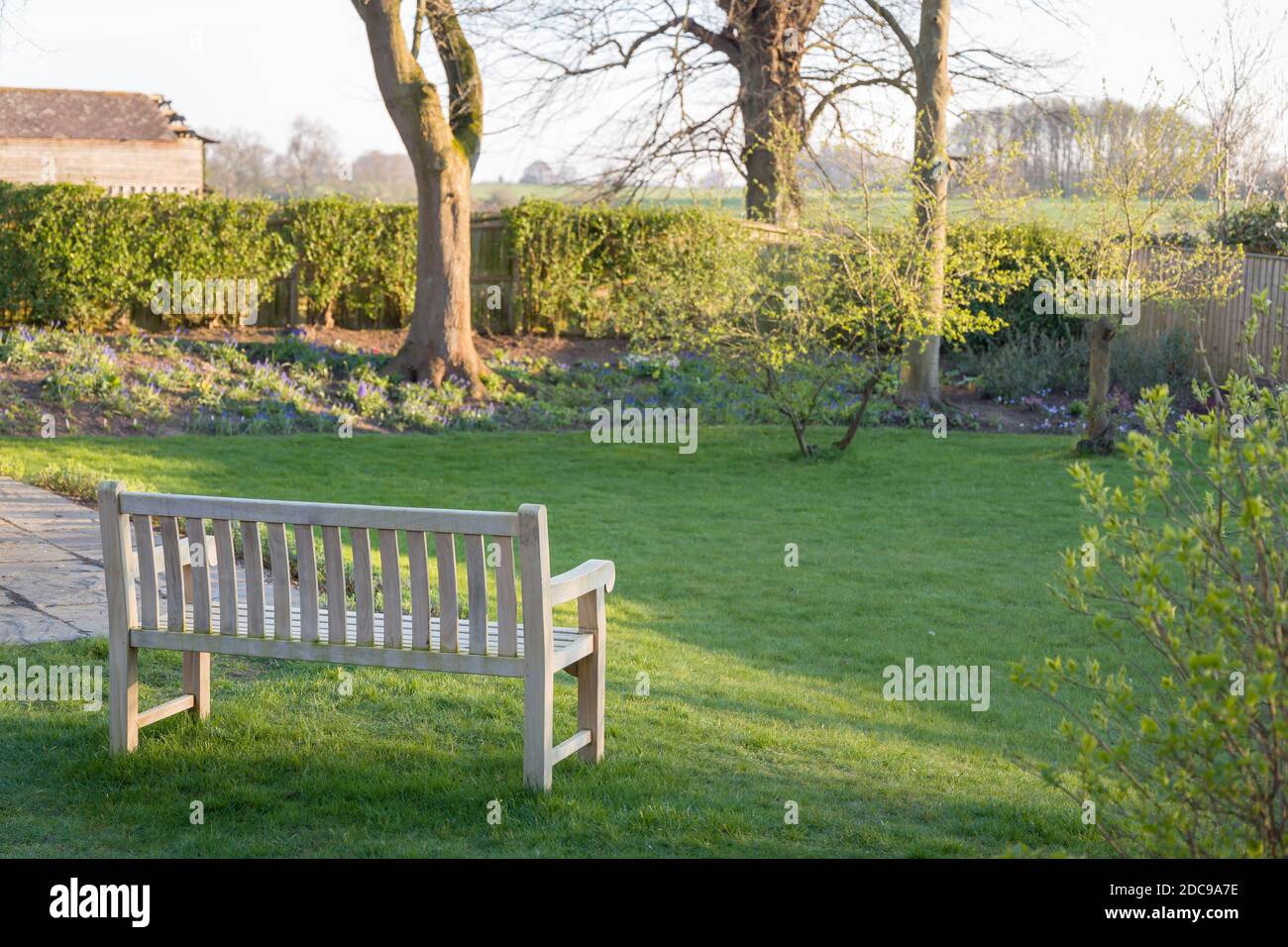 Large UK back garden in winter with a wooden garden bench on lawn, with ...