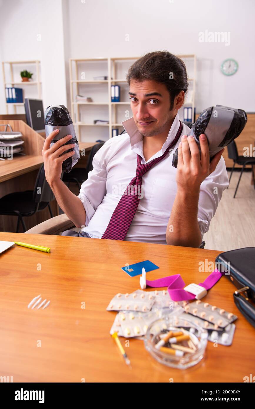 Young drug addicted male employee sitting at workplace Stock Photo - Alamy