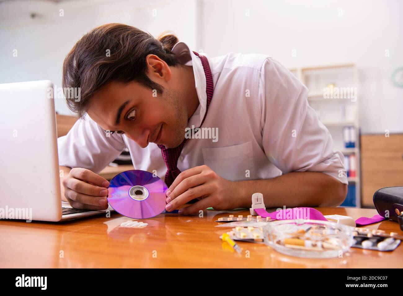 Young drug addicted male employee sitting at workplace Stock Photo - Alamy