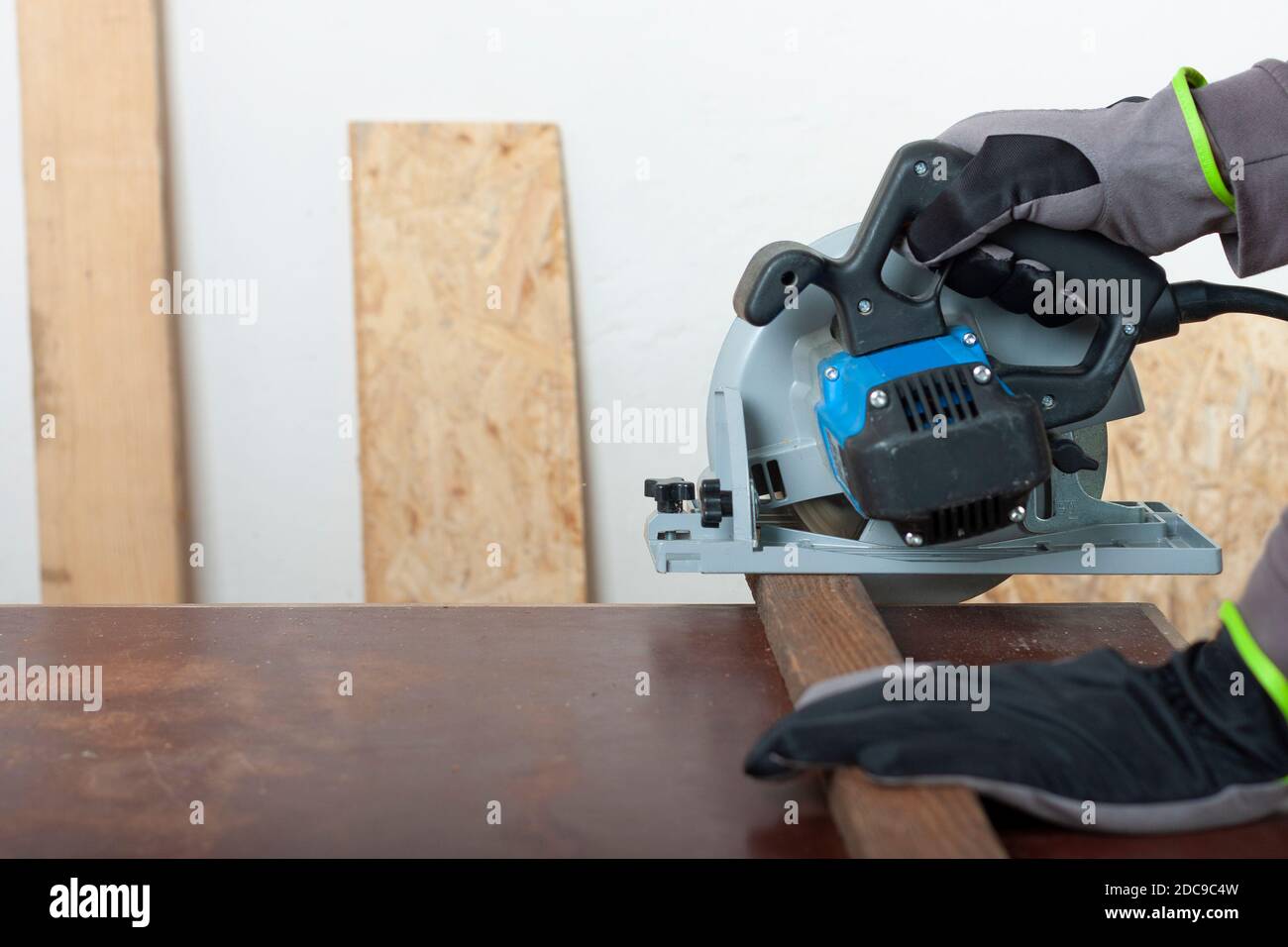 Carpenter cuts wood lath electric hand tool circular saw on desk, on ...