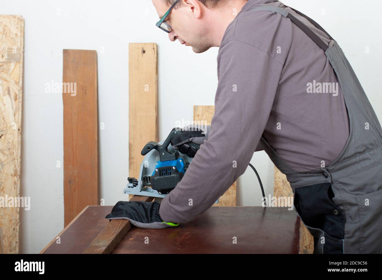 Carpenter cuts wood lath electric hand tool circular saw on desk, on ...