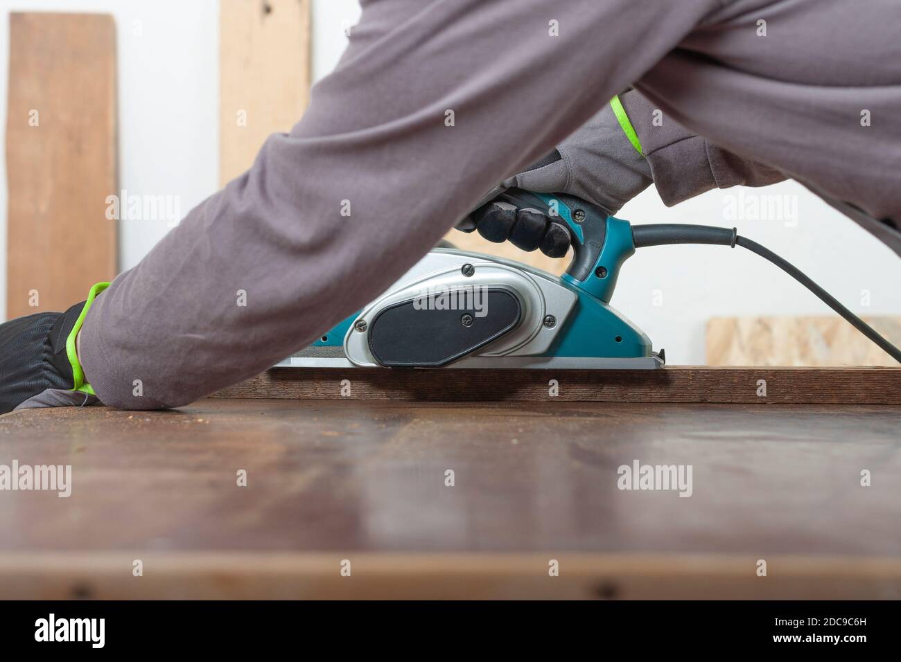 Carpenter working with electric planer on wood lath on desk, on ...