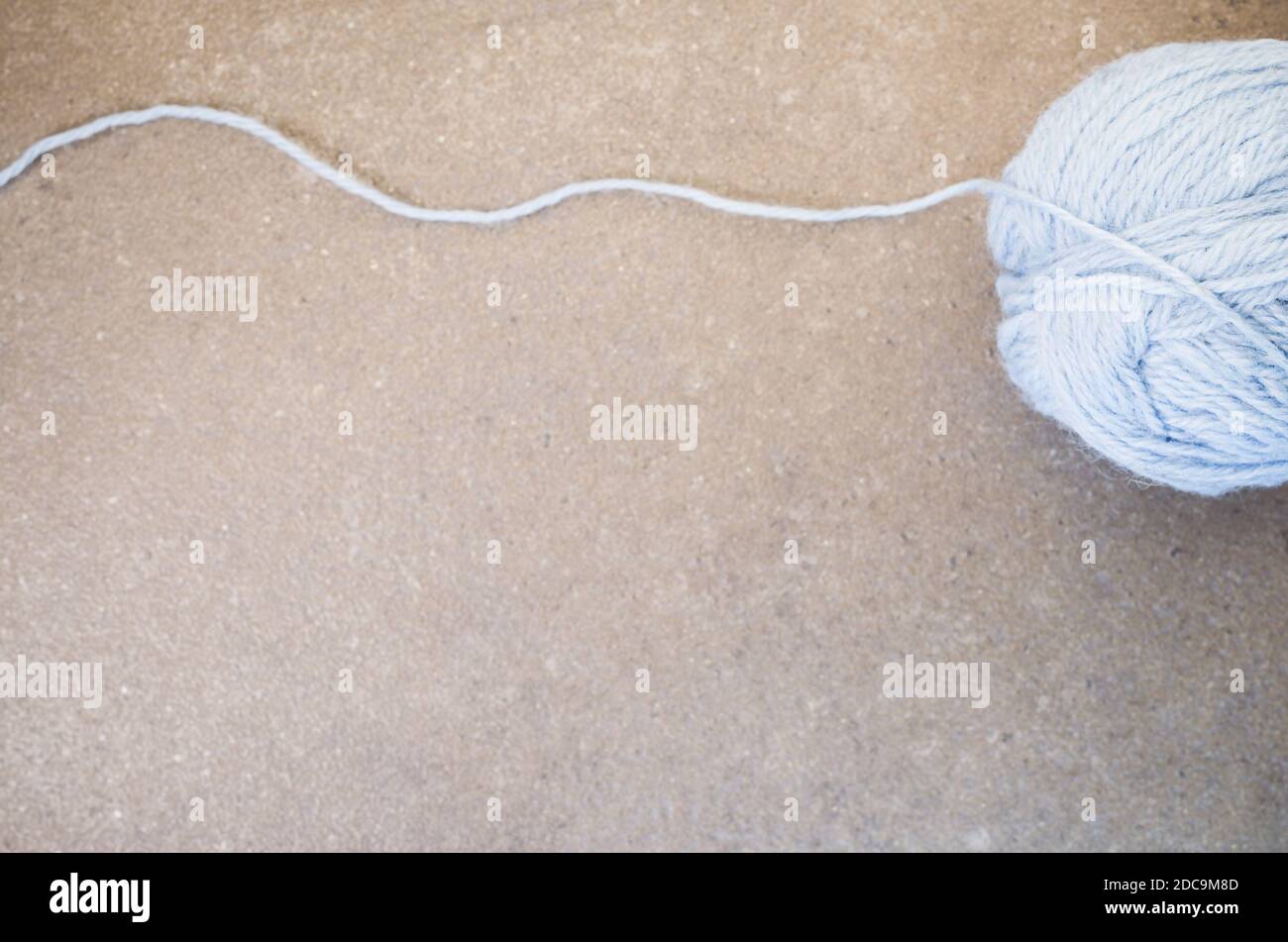 A top view of light blue yarn on a rough-textured surface with copy ...