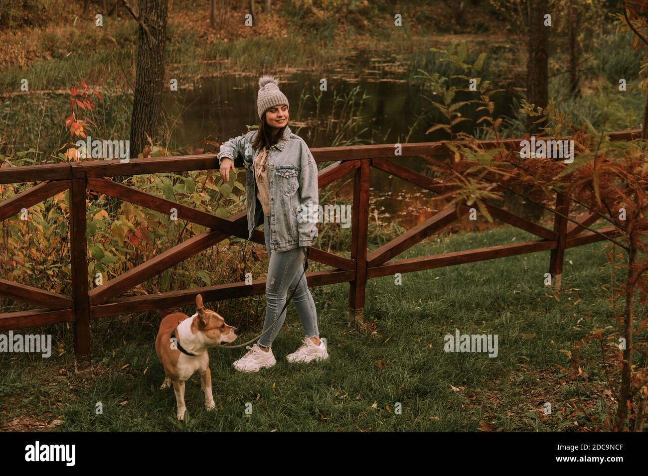 A beautiful modern teenage girl with a hat in a denim coat leaning ...