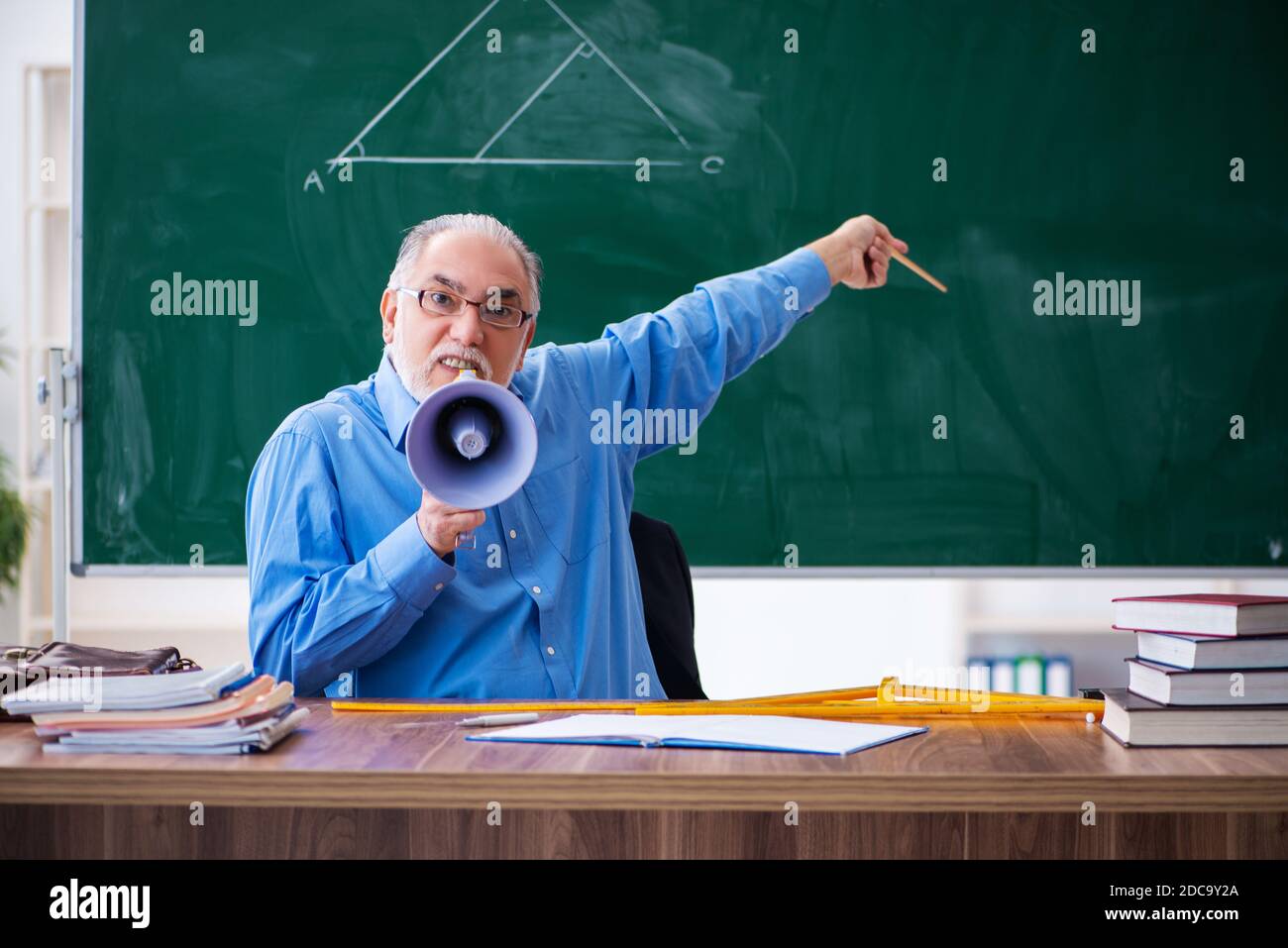 Angry male math teacher holding megaphone Stock Photo - Alamy