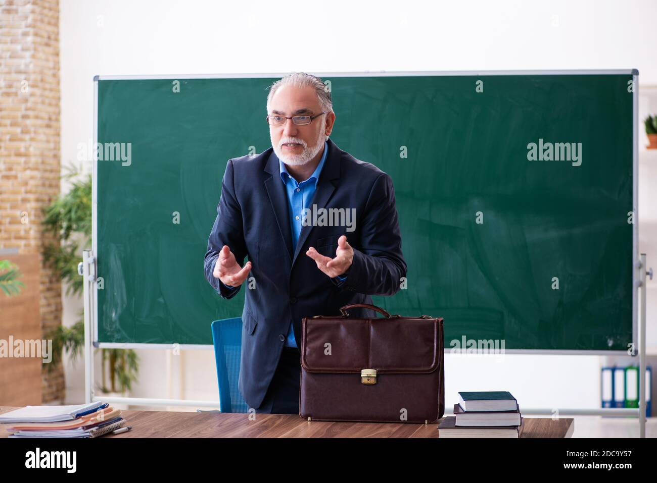 Aged male math teacher in the classroom Stock Photo - Alamy