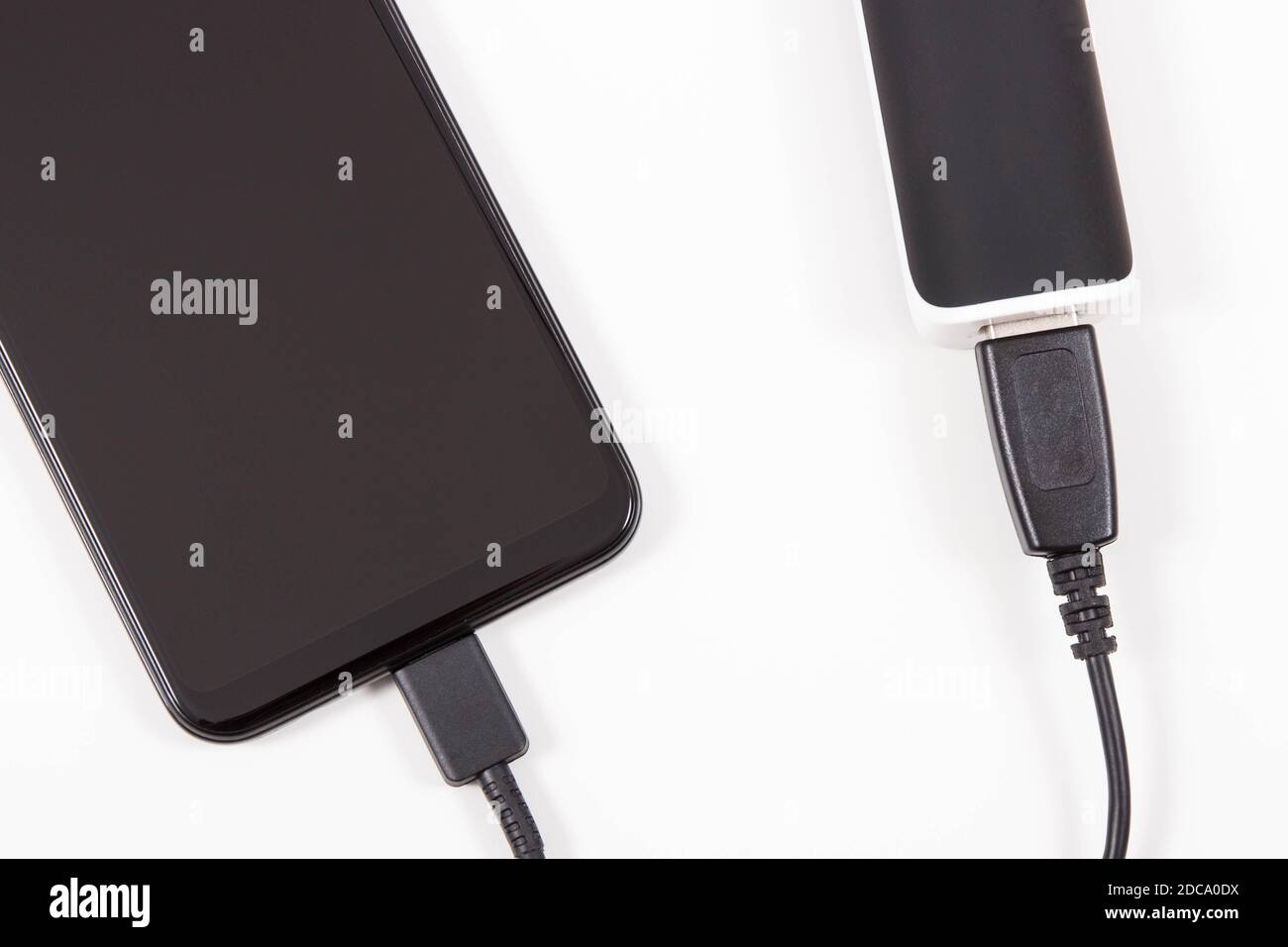 Smartphone with connected plug of powerbank. Telephone charging. White ...