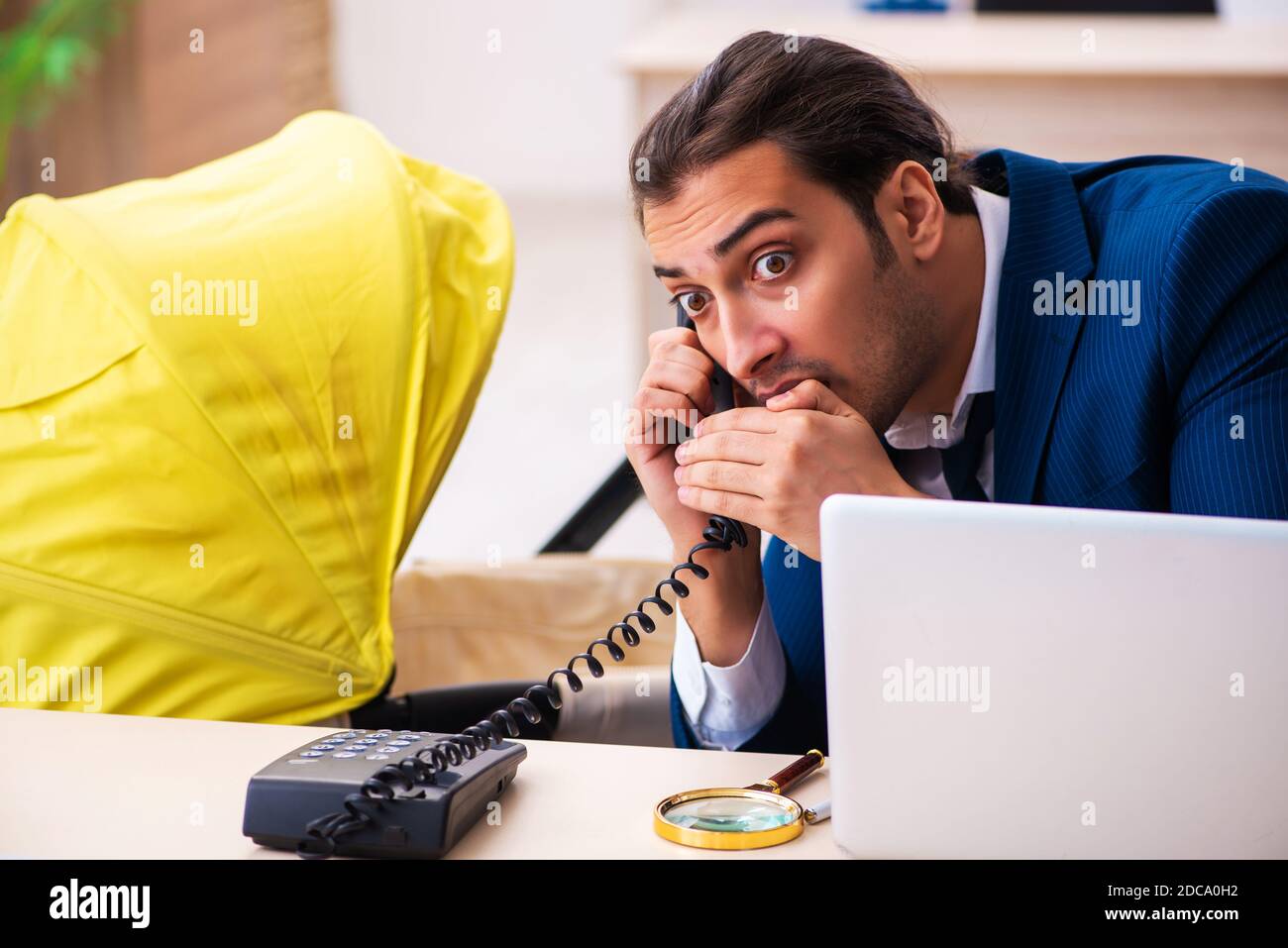 Young employee looking after kid at workplace Stock Photo - Alamy