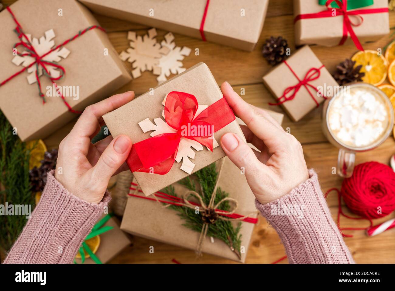 Female hands holding gift box wrapped in kraft paper and tied with ...