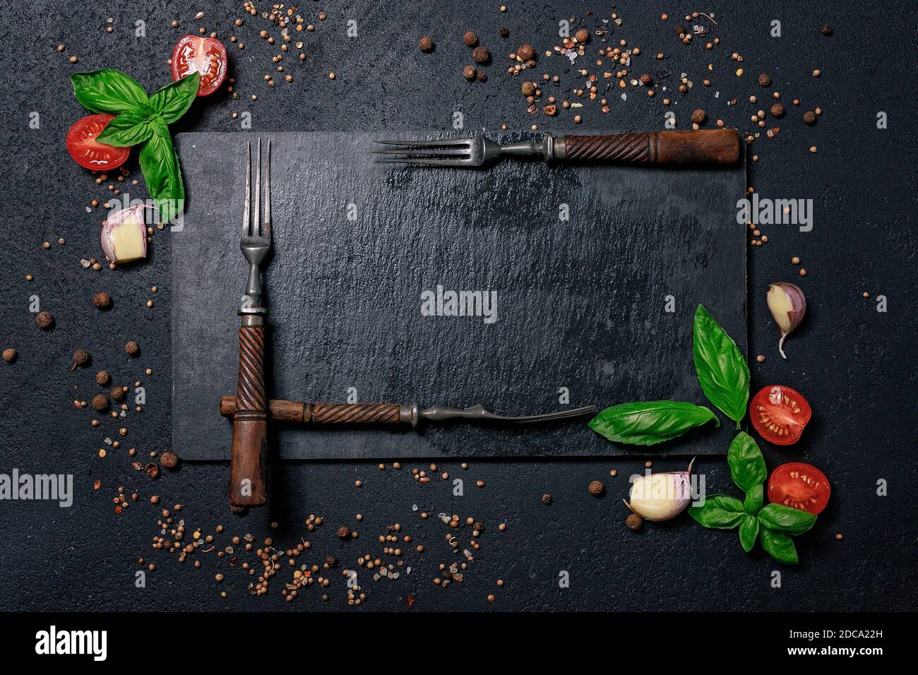 Stone cutting board and forks. Spices and herbs on a dark background ...