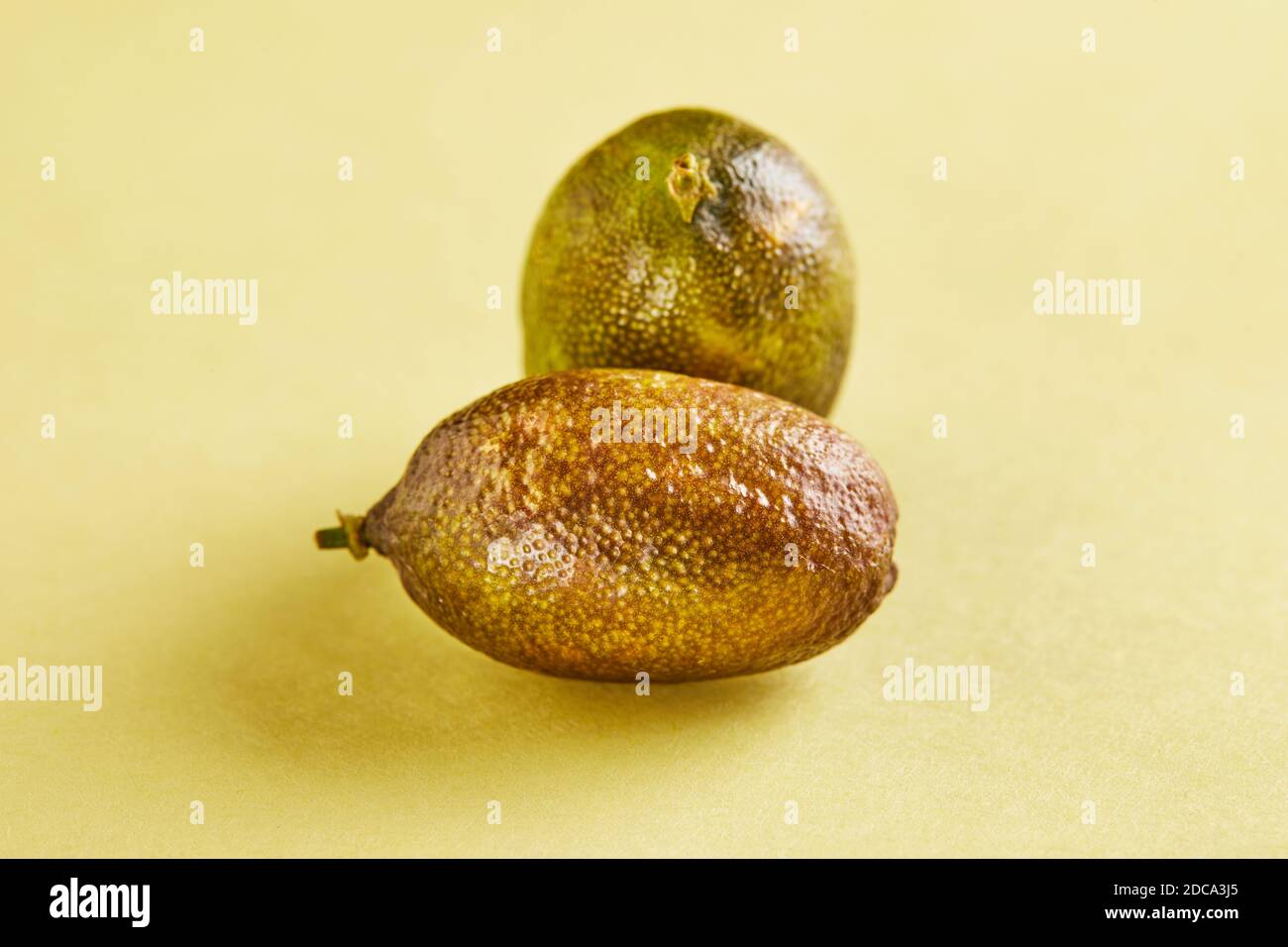 Ripe fresh mini lemons on a yellow background with a shadow Stock Photo ...