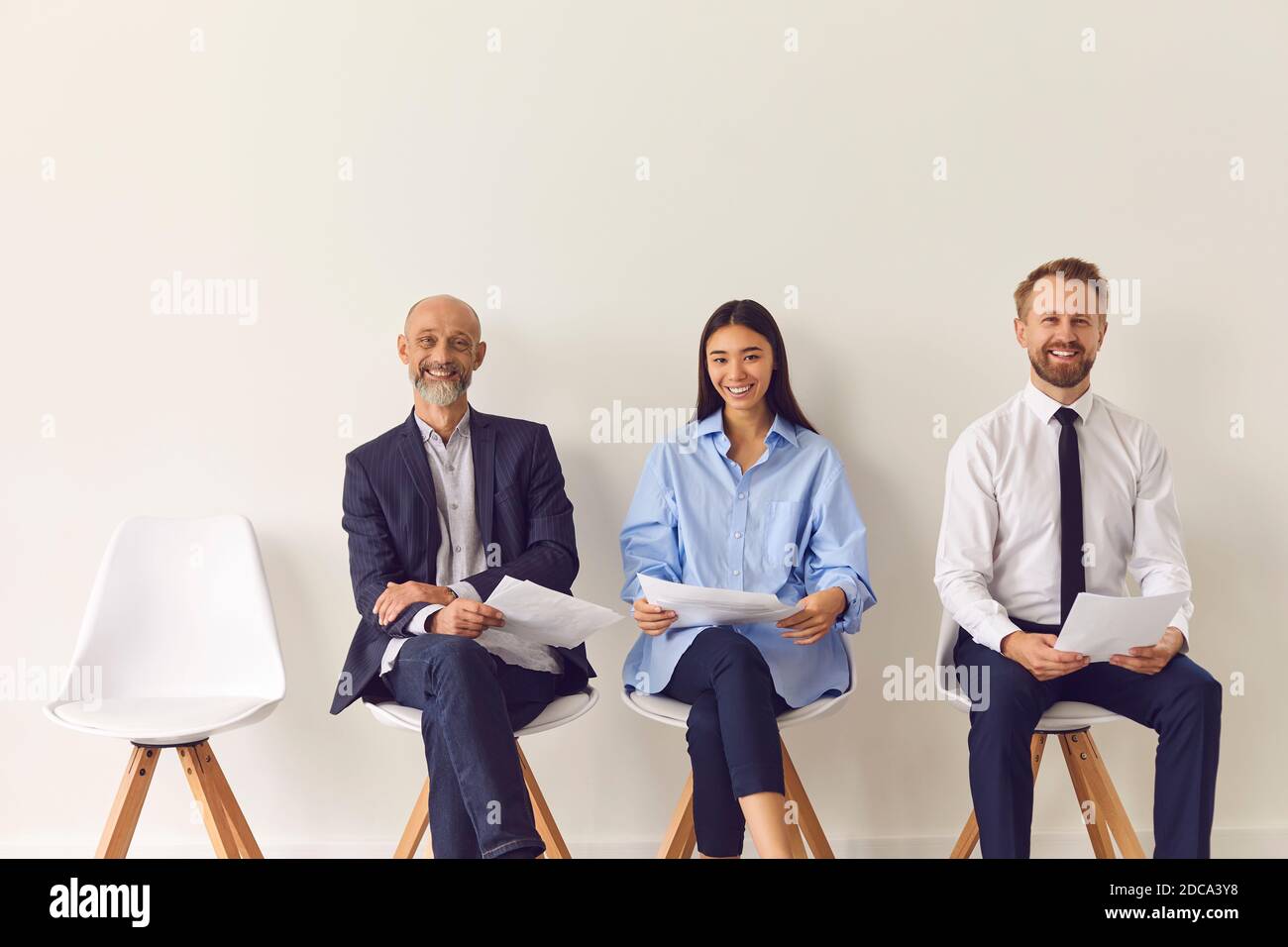 Three positive candidates of different ages sitting on chairs waiting ...