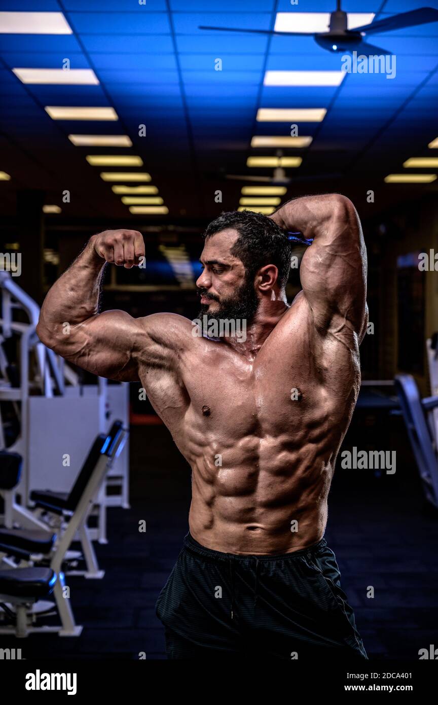 strong young athlete with beard showing sport physique in athletic gym ...