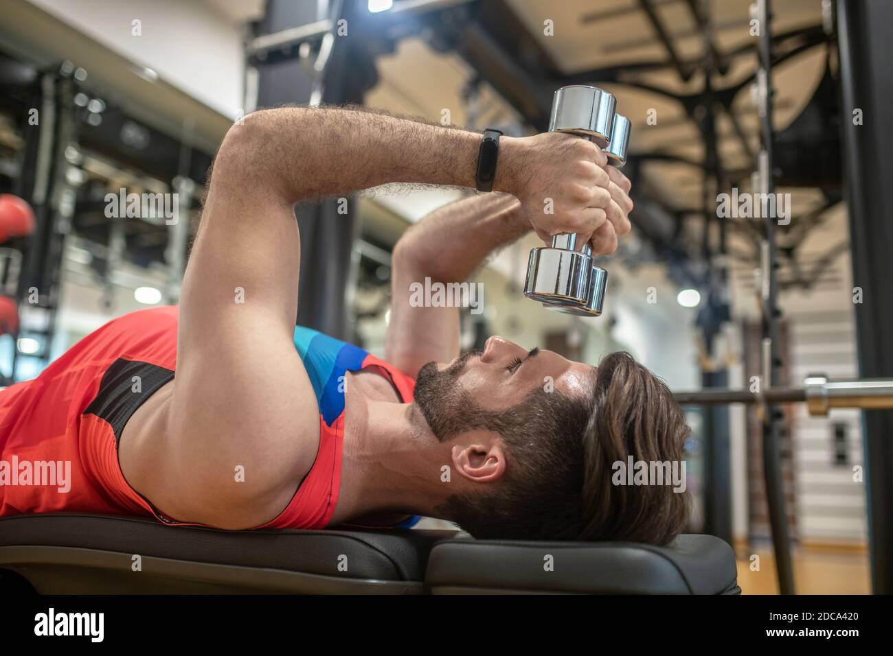 Young dark-haired man in bright tshirt working on his body in gym Stock ...