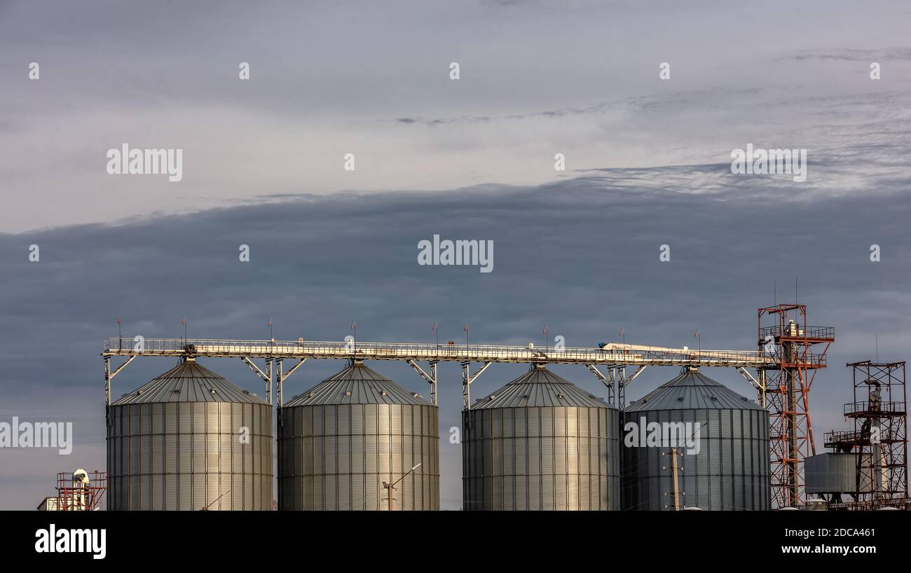 Low angle shot of grain storage units. Grey cloudy sky as a background ...