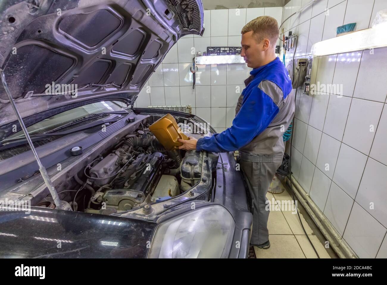 Car mechanic replacing and pouring oil into engine at car service ...