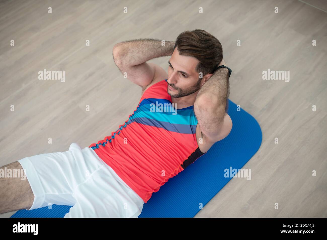Bearded young male doing abs exercises on blue mat Stock Photo - Alamy