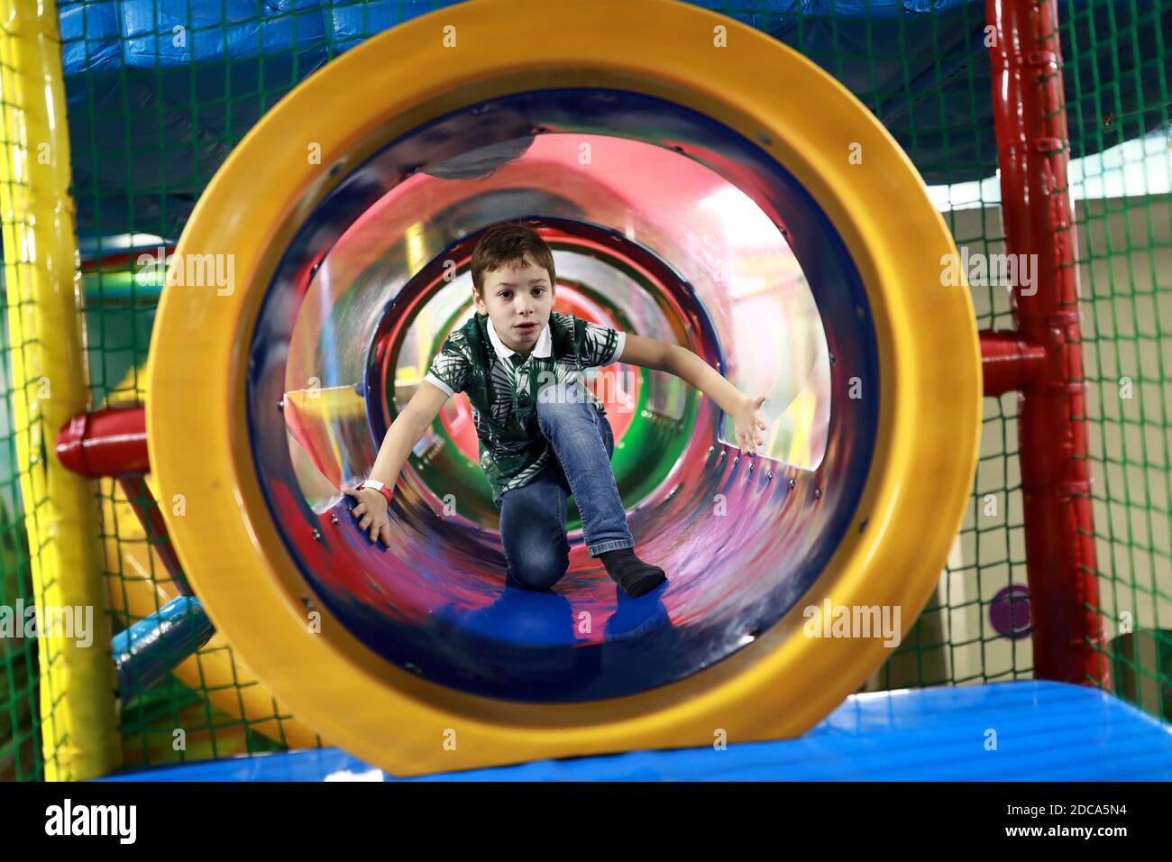 Kid sitting in tube on indoor playground Stock Photo - Alamy
