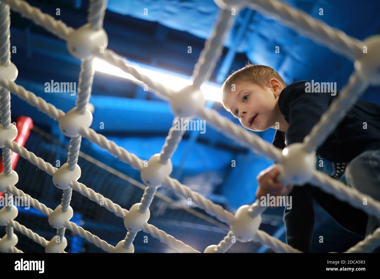 Kid crawling on rope net on playground Stock Photo - Alamy