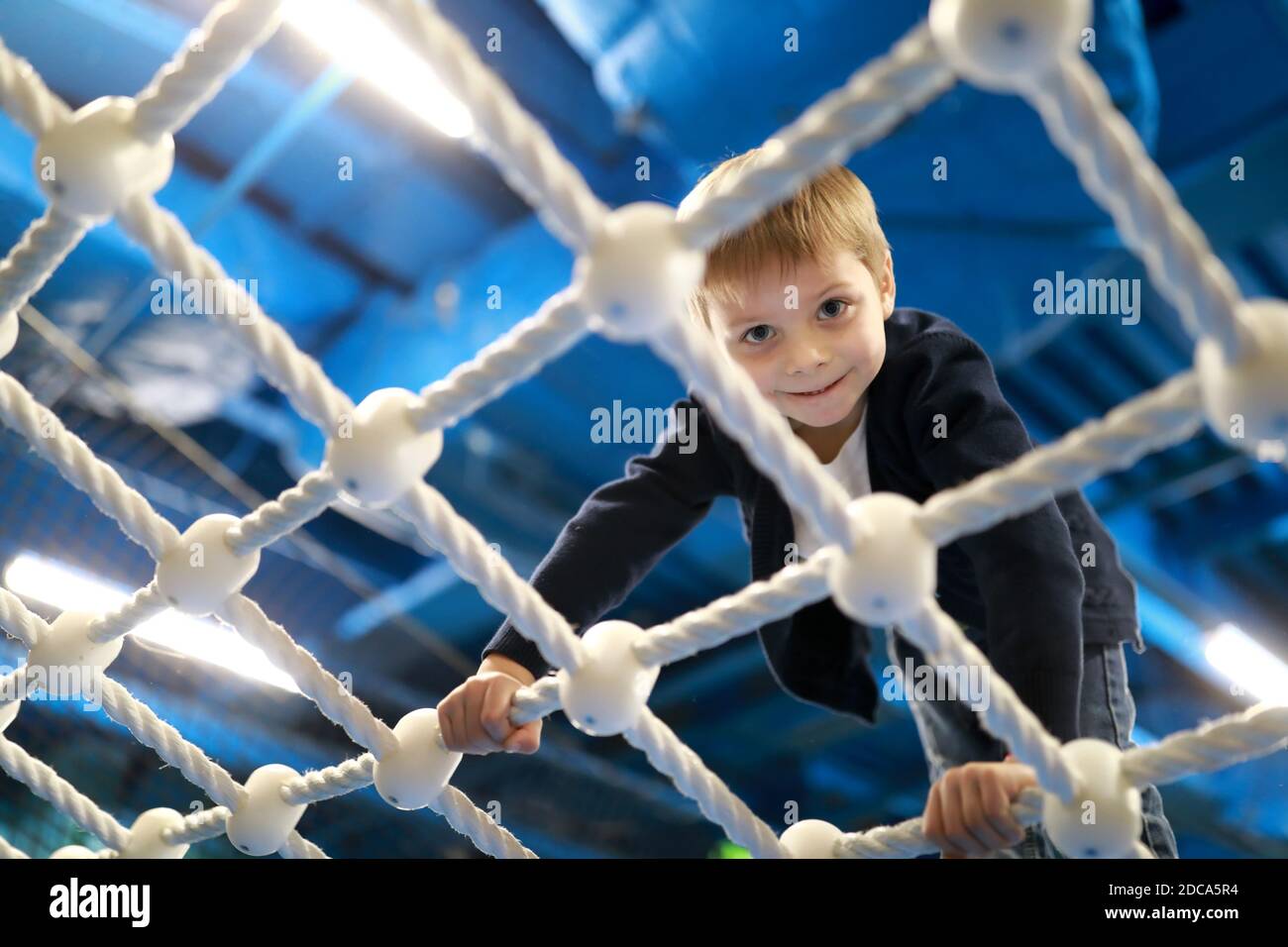Boy crawling on rope net on playground Stock Photo - Alamy