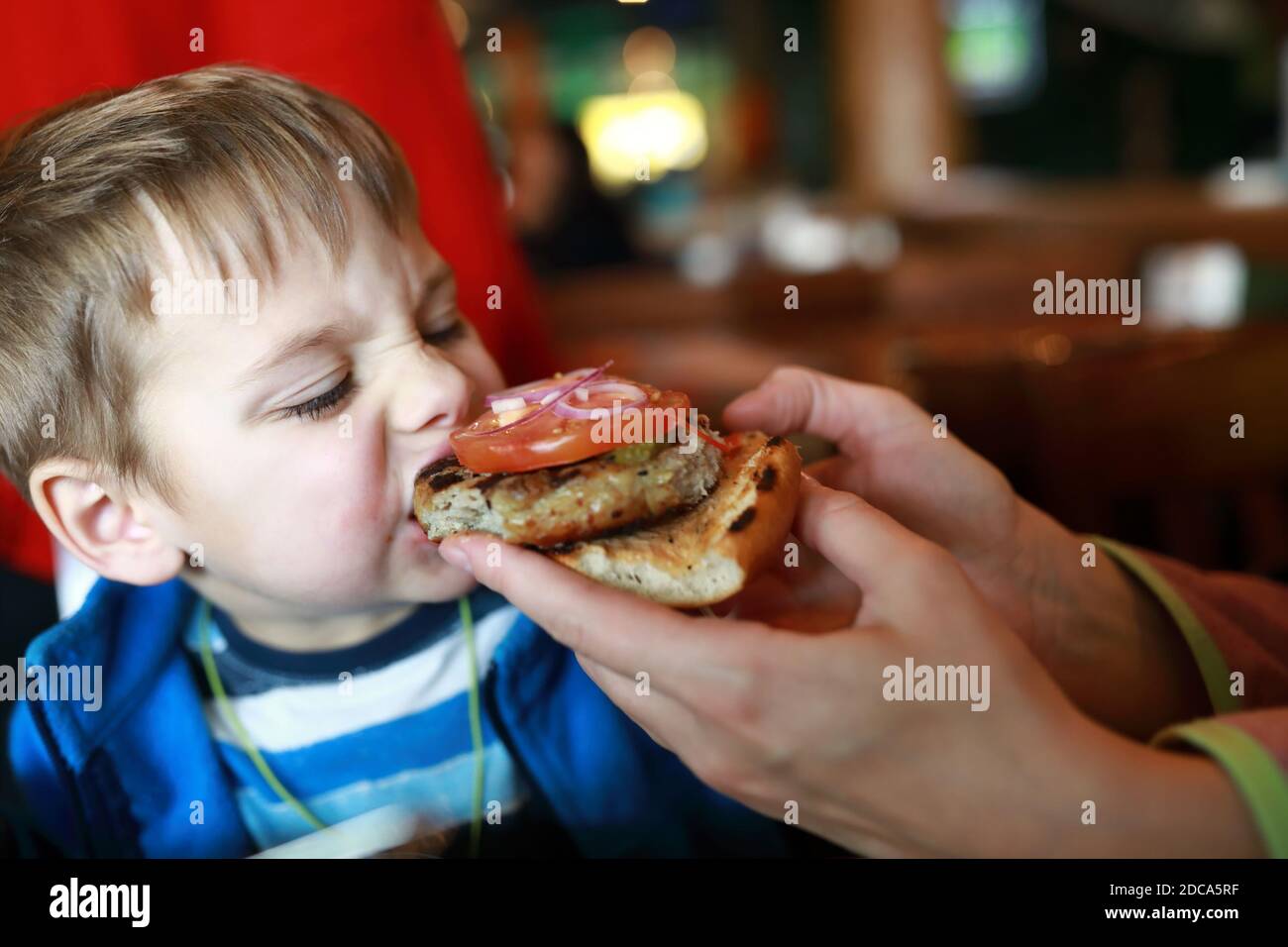 Boy is eating burger in a restaurant Stock Photo - Alamy