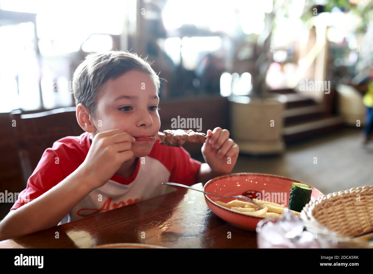 Child eating chicken kebab in a restaurant Stock Photo - Alamy