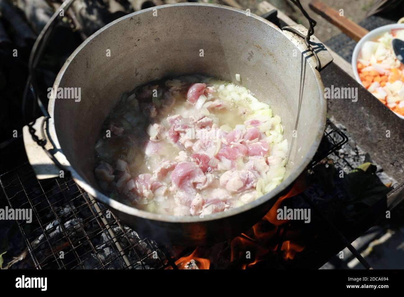 Frying meat with onions in cauldron on fire for pilaf Stock Photo - Alamy