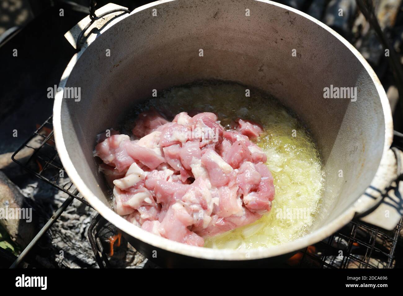 Frying meat in cauldron on fire for pilaf Stock Photo - Alamy