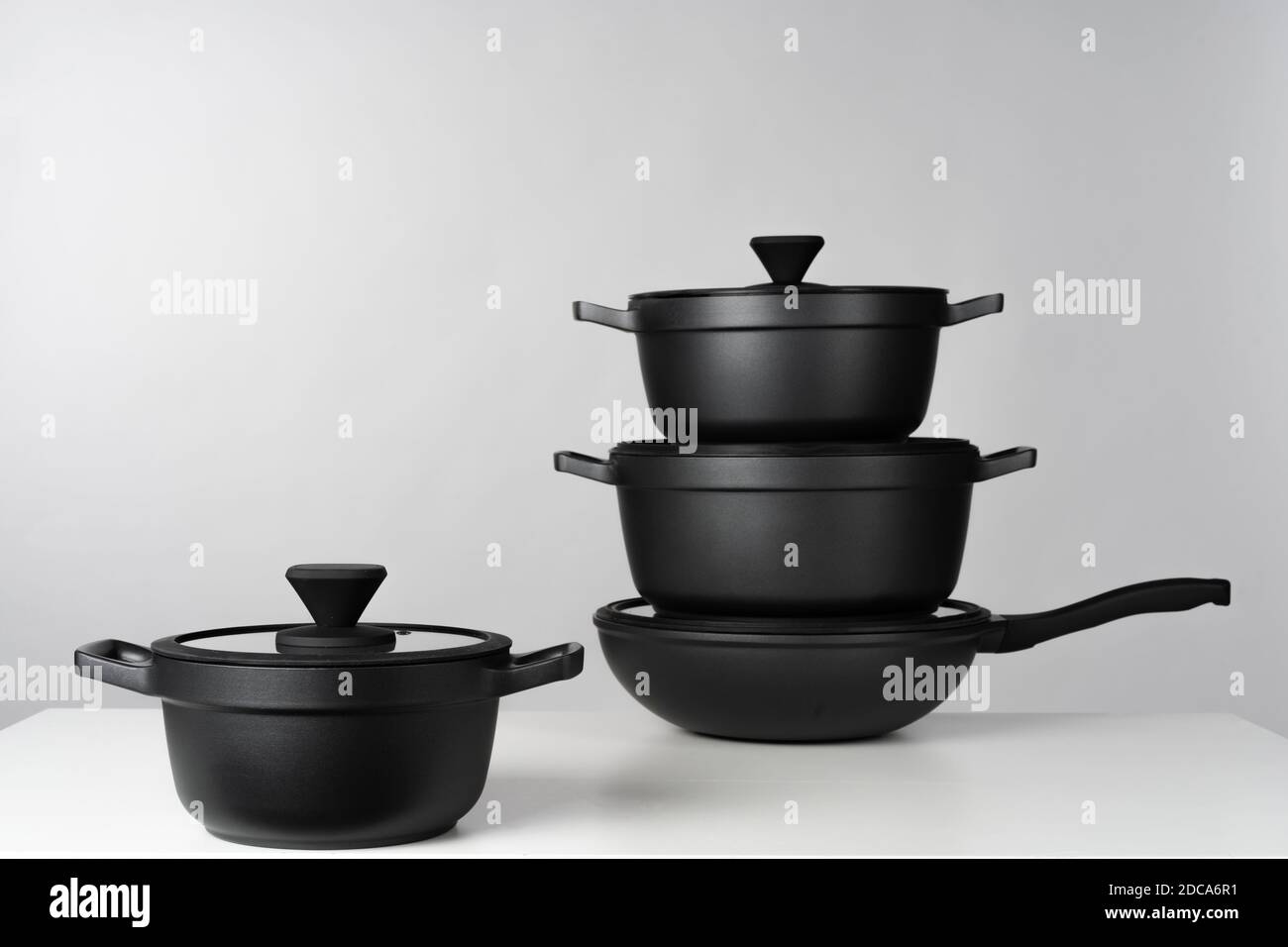 Black cooking pots on grey background front view Stock Photo - Alamy