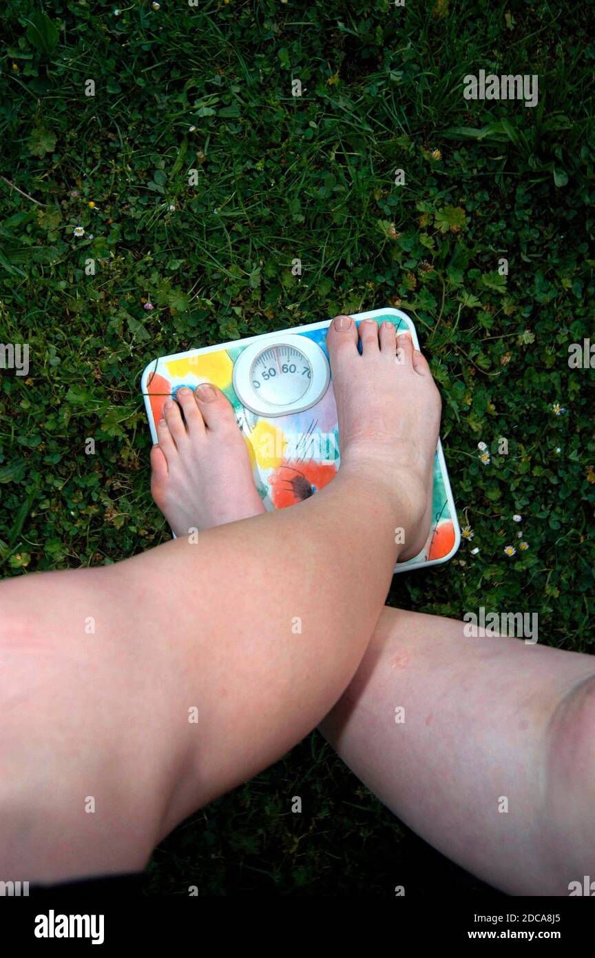 an overweight person standing on a weighing scale for weight ...