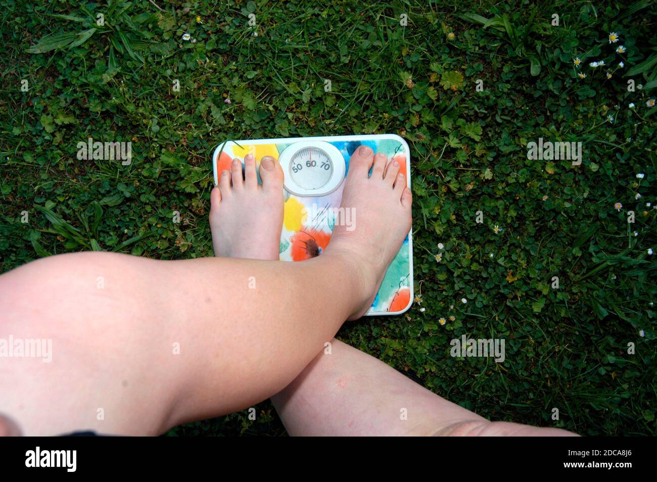 an overweight person standing on a weighing scale for weight ...