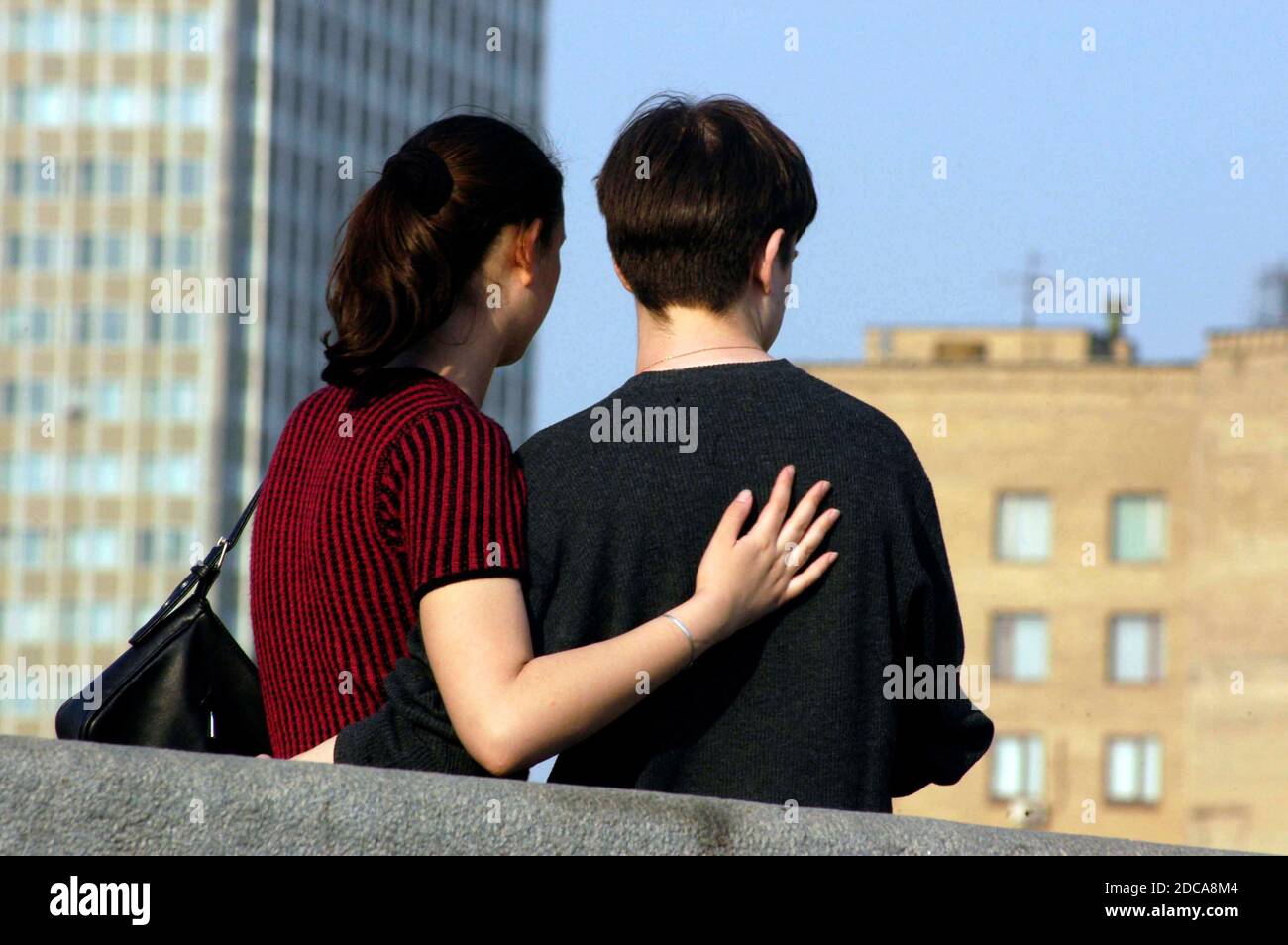 a couple in a city, she is touching his back Stock Photo - Alamy