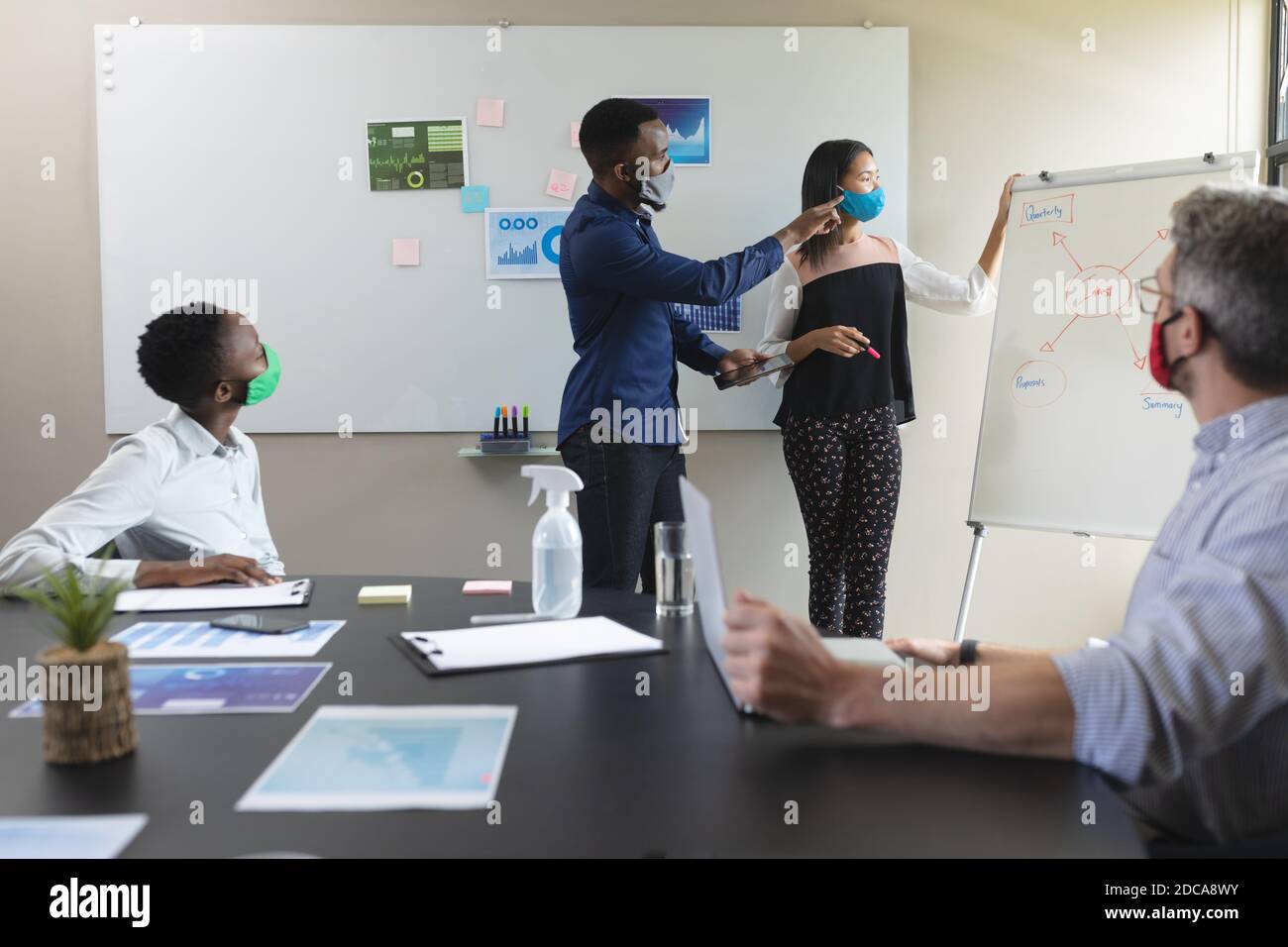 Diverse male and female colleagues wearing face masks giving ...